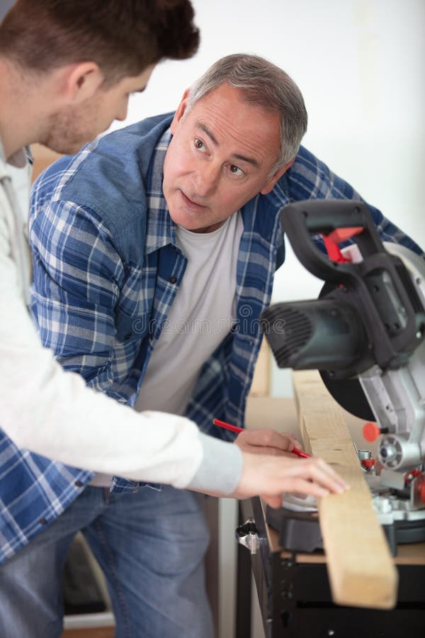 Carpenter with Apprentice Cutting Wood in Workshop Stock Image - Image ...