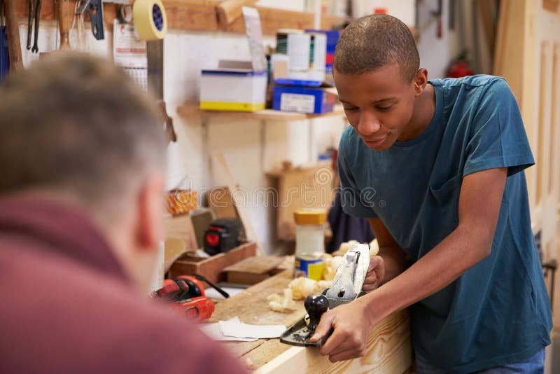 Carpenter with Apprentice Planing Wood in Workshop Stock Photo - Image ...