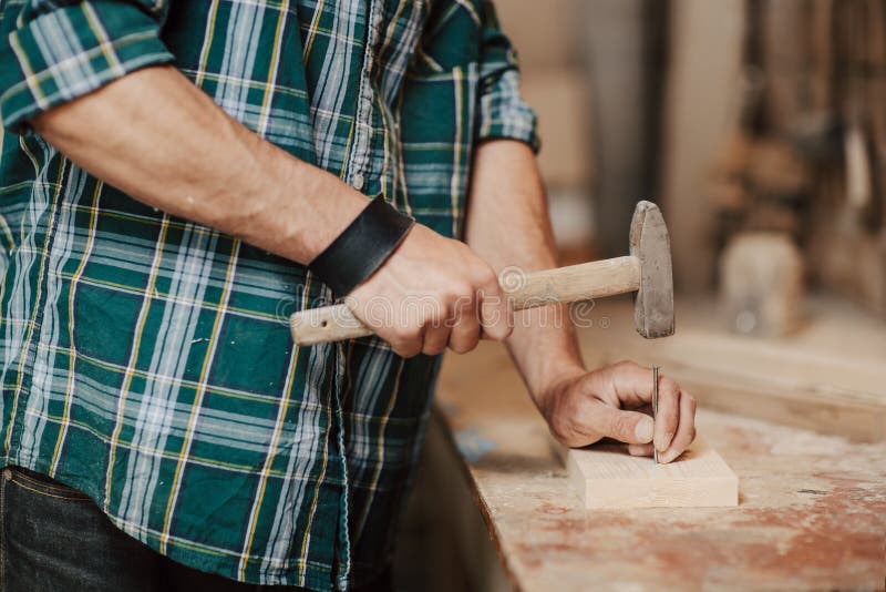 Carpenter Builder Nailing Wood Board with Hammer on a Wooden Table in ...