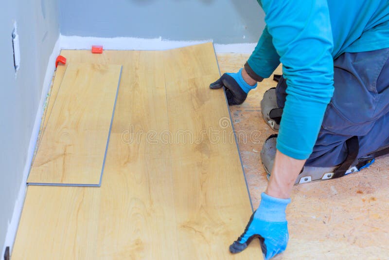 Worker Installing Laminate Flooring in a Room with Gray Walls and ...