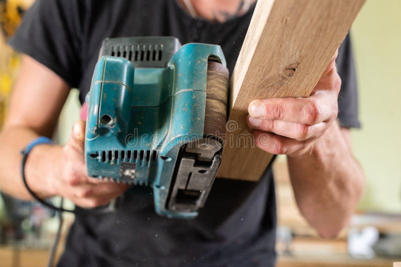 A Carpenter Grinds an Oak Plank Part with a Hand Grinder Stock Photo ...