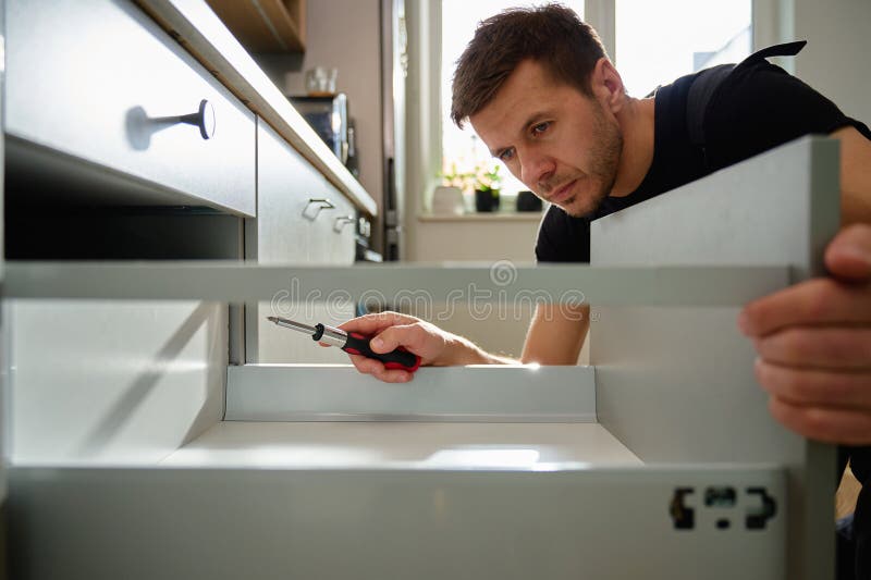 Carpenter Installing and Adjusting Drawer Front in Modern Kitchen ...