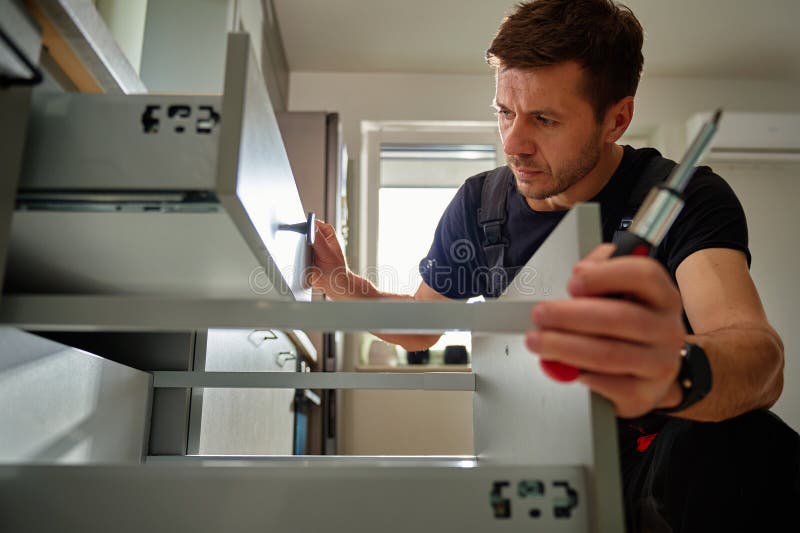 Carpenter Installing and Adjusting Drawer Front in Modern Kitchen ...