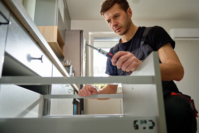 Carpenter Installing and Adjusting Drawer Front in Modern Kitchen ...