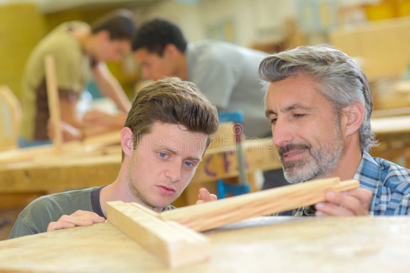 Carpenter Looking at Apprentice`s Work Stock Image - Image of crouching ...