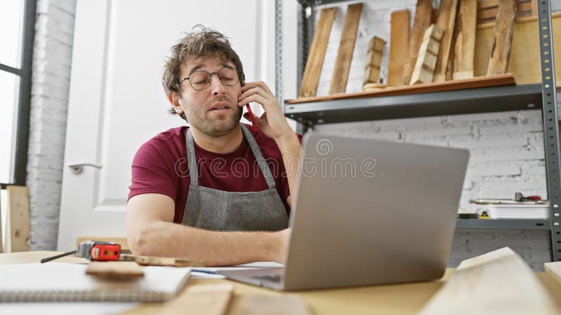 Carpenter Multitasks between a Phone Call and Laptop in a Workshop ...