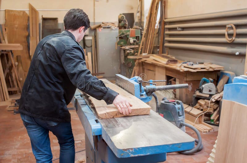 Carpenter Plans a Board in a Carpentry Workshop on a Large Stationary ...