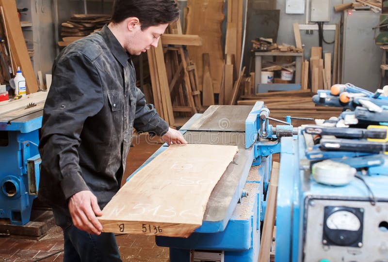 Carpenter Plans a Board in a Carpentry Workshop on a Large Stationary ...