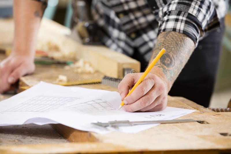 Carpenter Plans Project and Writes at Drawings in Workshop Stock Photo ...
