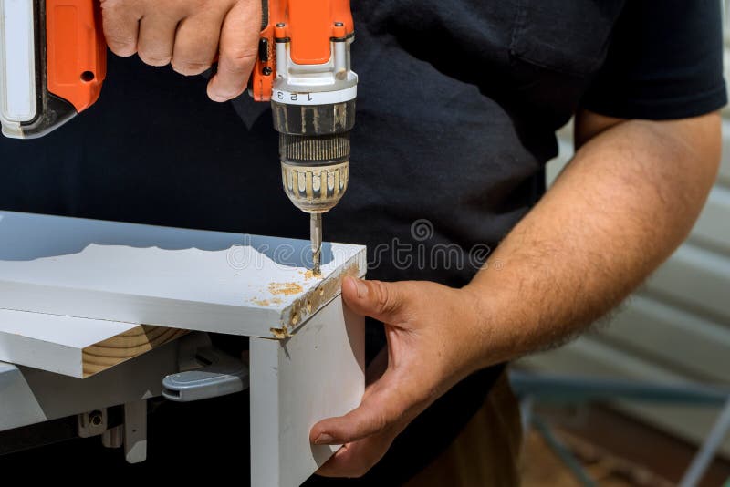 A Carpenter is Using a Screwdriver To Drill Holes into Wooden Boards in ...