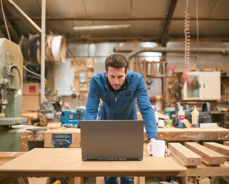 Carpenter Working in Woodwork Workshop Using Laptop with Cup of Coffee ...