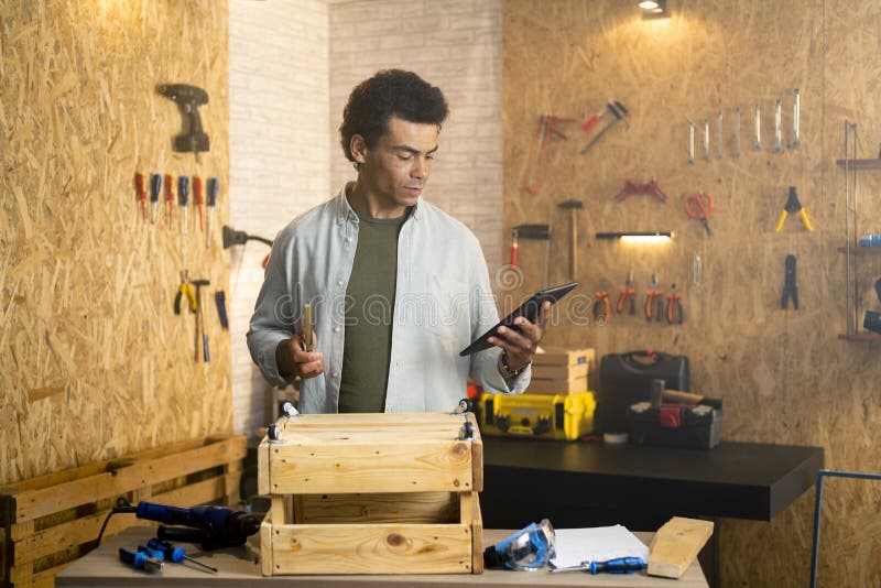 Carpenter in Workshop Measuring a Crate and Looking in To Tablet Stock ...