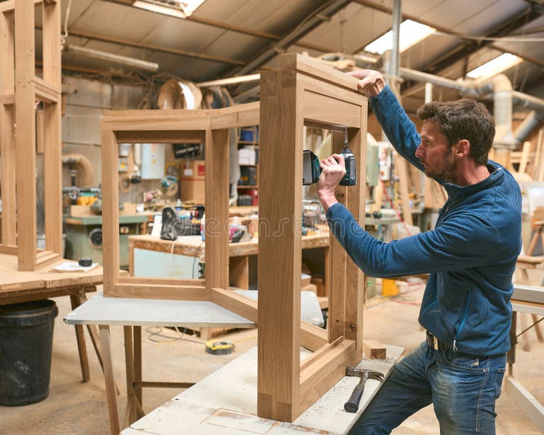 Carpenter in Workshop Using Drill To Attach Piece of Wood To Window ...
