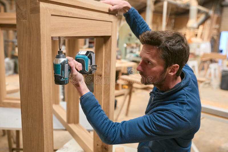 Carpenter in Workshop Using Drill To Attach Piece of Wood To Window ...