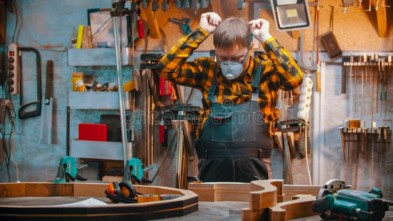 Carpentry Indoors - a Man Woodworker Put on a Protective Mask Stock ...