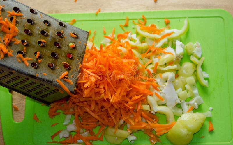 Carrots Grated on a Grater with Chopped Pepper on a Green Background ...