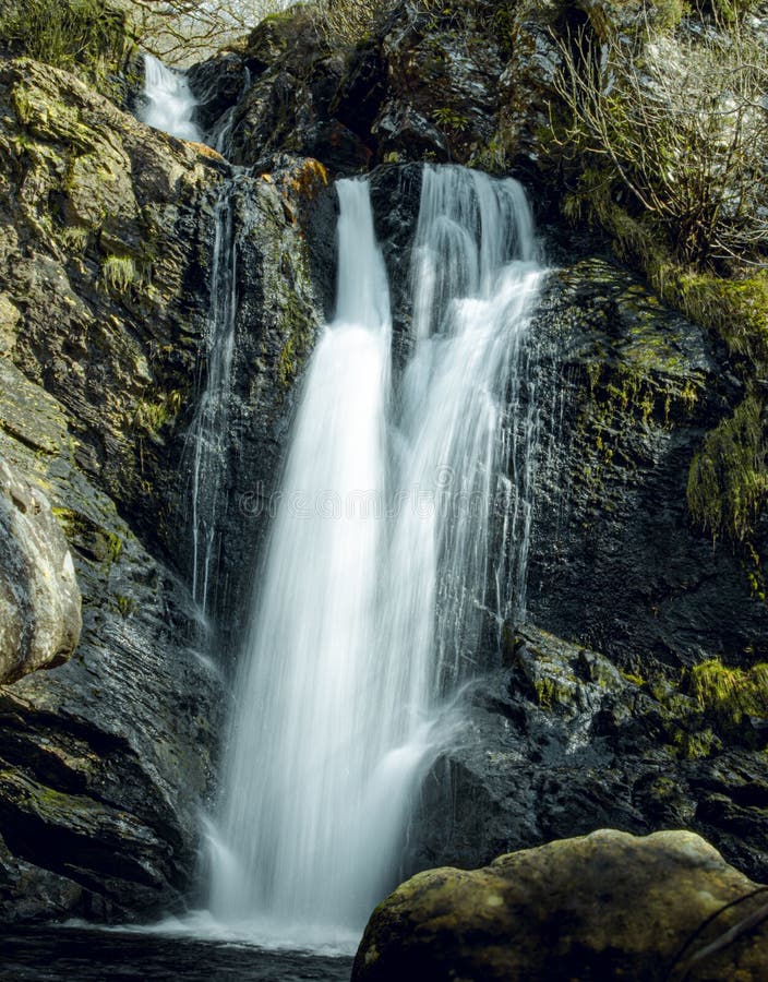 Cascading Waterfall Trickling Down a Rocky Surface into a River Below ...