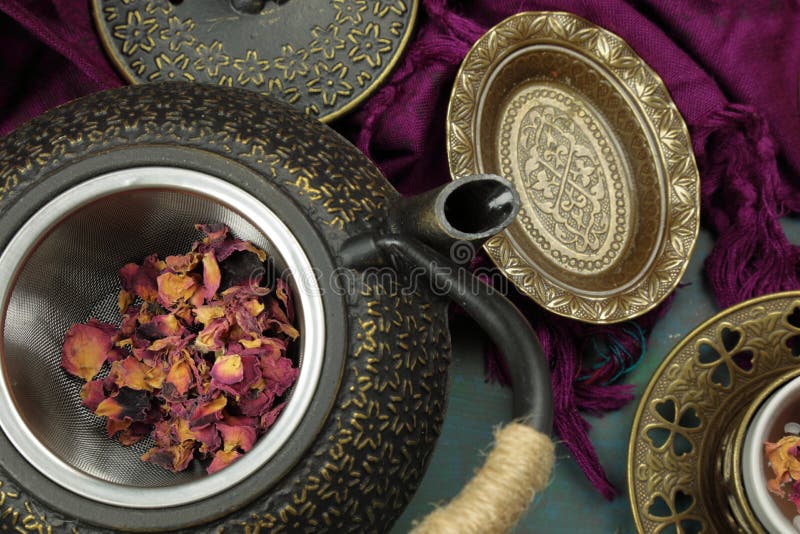 A Cast Iron Teapot Kettle with a Cup of Rose Tea and Some Rose Petals ...