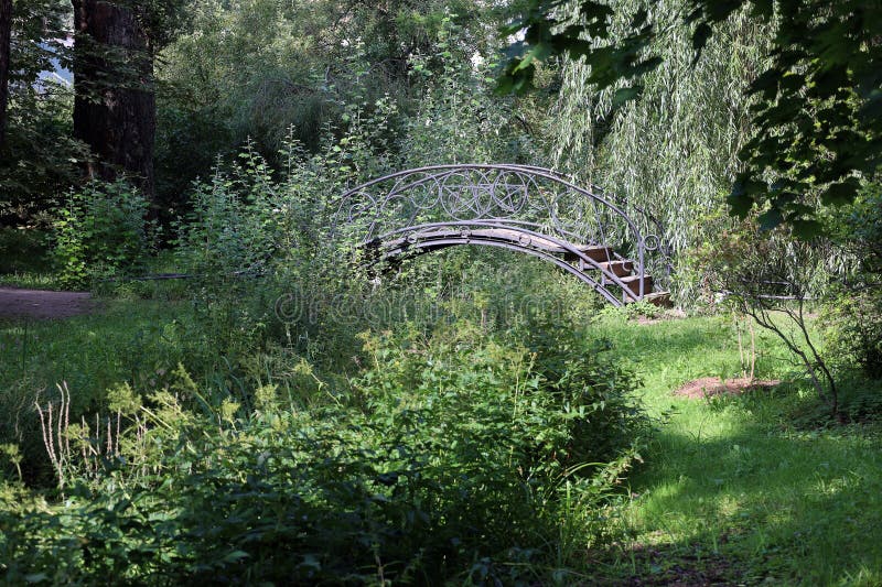 Cast Iron Twisted Bridge Over a Stream in an Overgrown Park Stock Photo ...
