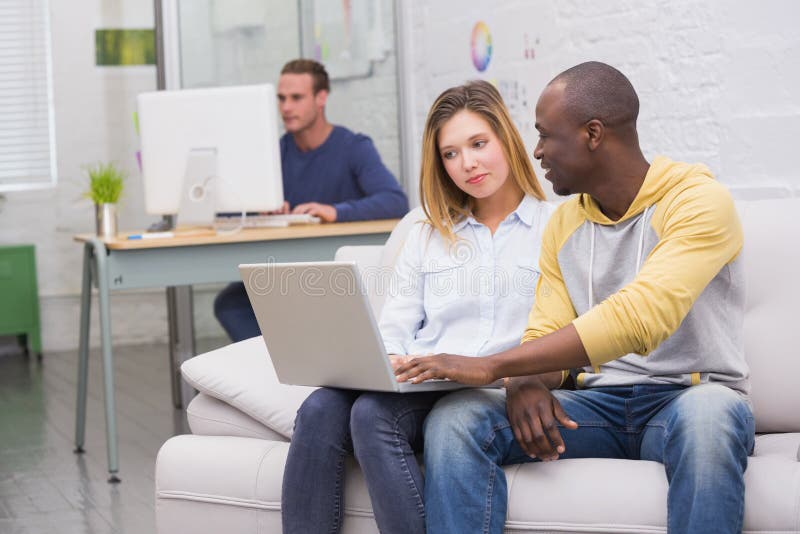 Casual Colleagues Using Laptop on Couch in Office Stock Photo - Image ...