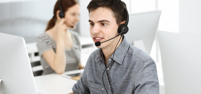 Casual Dressed Young Man Using Headset and Computer while Talking with ...