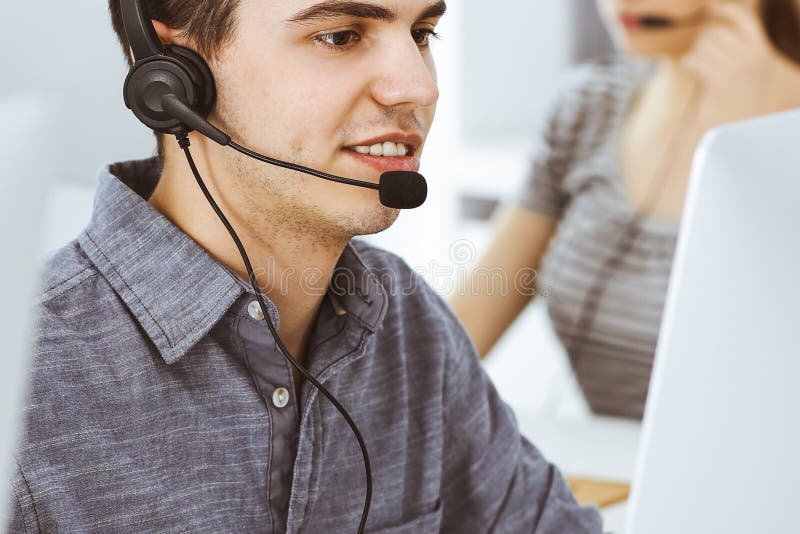 Casual Dressed Young Man Using Headset and Computer while Talking with ...