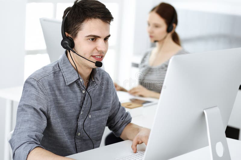 Casual Dressed Young Man Using Headset and Computer while Talking with ...