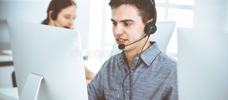 Casual Dressed Young Man Using Headset and Computer while Talking with ...
