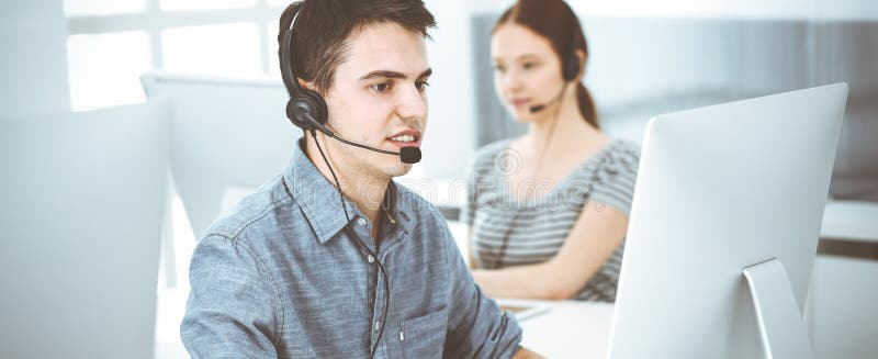 Casual Dressed Young Man Using Headset and Computer while Talking with ...