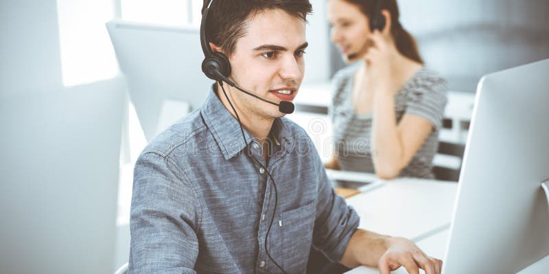 Casual Dressed Young Man Using Headset and Computer while Talking with ...