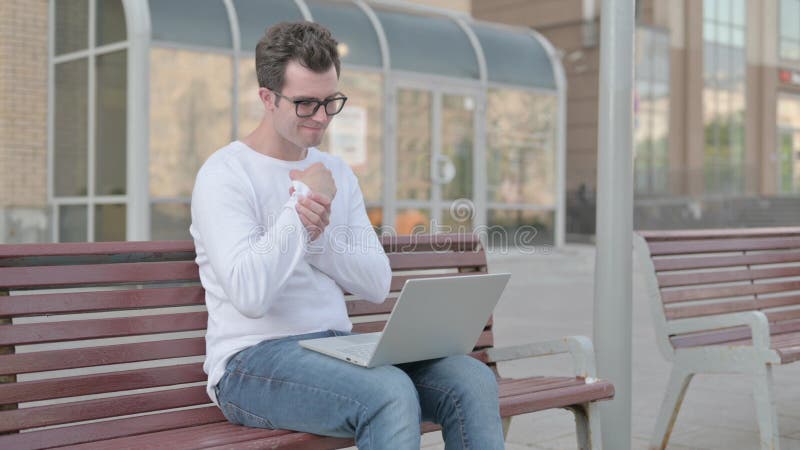 Young Man with Wrist Pain Using Laptop while Sitting on Bench Stock ...