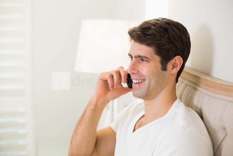 Casual Smiling Man Using Cellphone in Bed Stock Photo - Image of copy ...