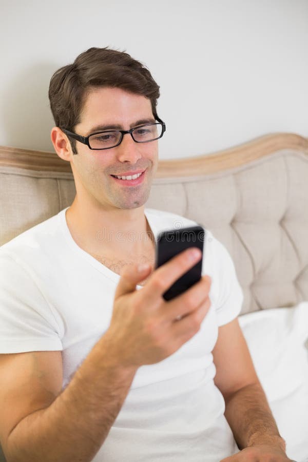 Casual Smiling Young Man Text Messaging in Bed Stock Photo - Image of ...