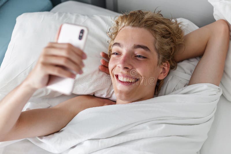Casual Smiling Young Man Text Messaging Phone in Bed at Home Stock ... Casual Smiling Young Man Text Messaging Phone in Bed at Home Stock ...