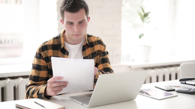 The Casual Young Man Doing Paperwork and Typing on Laptop Stock Image ...