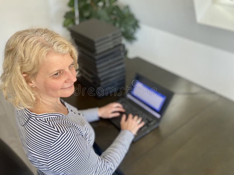 A Casually Dressed Caucasian Middle Aged Woman is Installing a Laptop ...