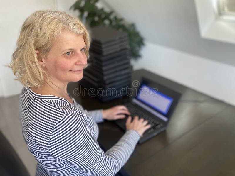 A Casually Dressed Caucasian Middle Aged Woman is Installing a Laptop ...