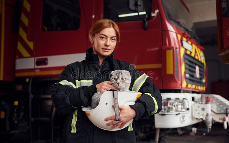 Cat is Inside of the Protective Helmet. Woman Firefighter in Uniform is ...