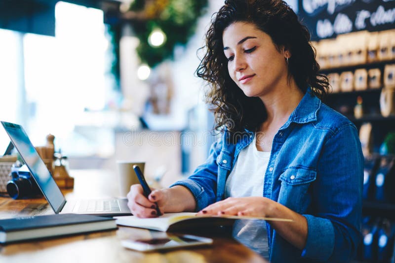 Caucaisan Female Student Writing Education Notes in Textbook while E ...