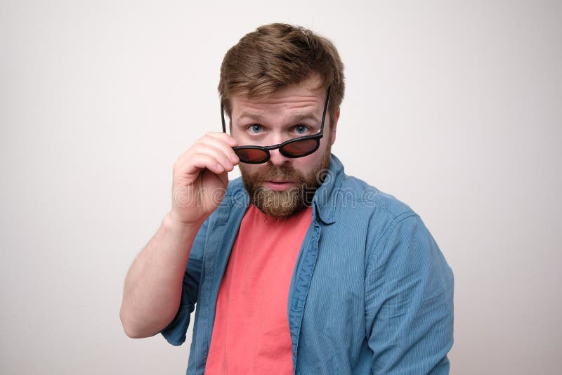 Caucasian Bearded Man Haughtily Looks Through Lowered Sunglasses