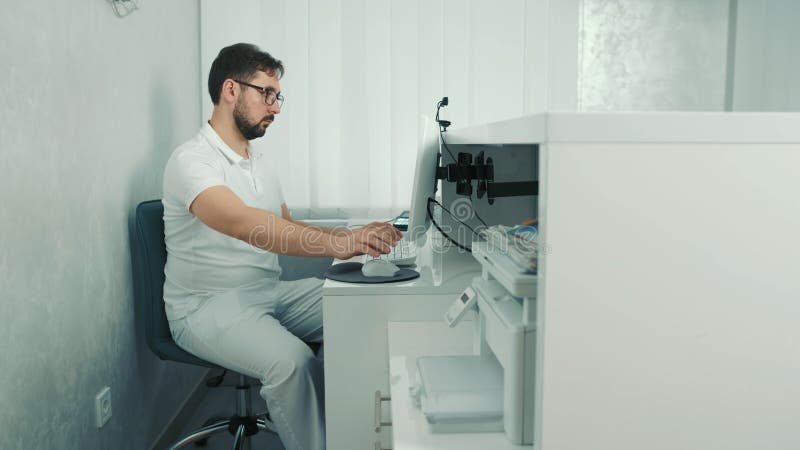 Caucasian Dentist Sitting at the Computer at the Reception and ...