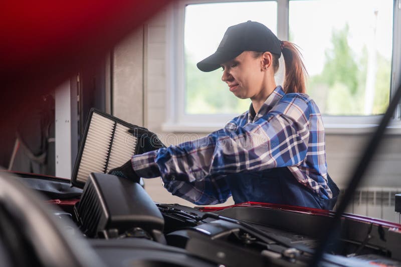 Caucasian Female Auto Mechanic Changes the Engine Air Filter in the Car ...