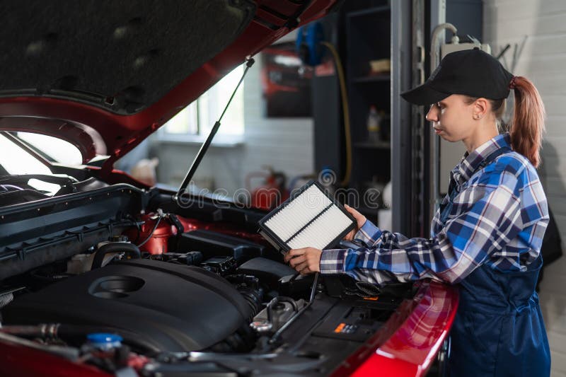 Caucasian Female Auto Mechanic Changes the Engine Air Filter in the Car ...