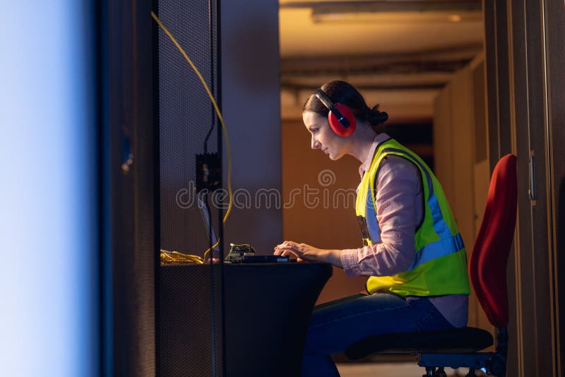 Caucasian Female Engineer Wearing Ear Plugs Using a Laptop in Computer ...