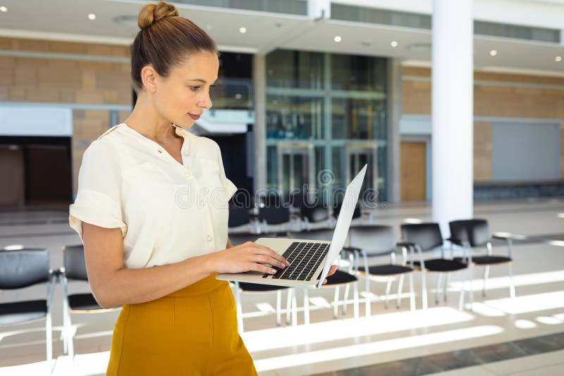 Caucasian Female Executive Looking at Computer while Standing in Empty ...