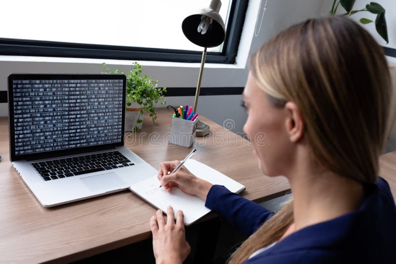 Caucasian Female Programmer Sitting At Desk Using Laptop With Coding