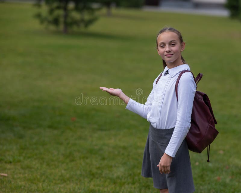 Caucasian Girl in Uniform and with a Backpack Points To an Empty Place ...