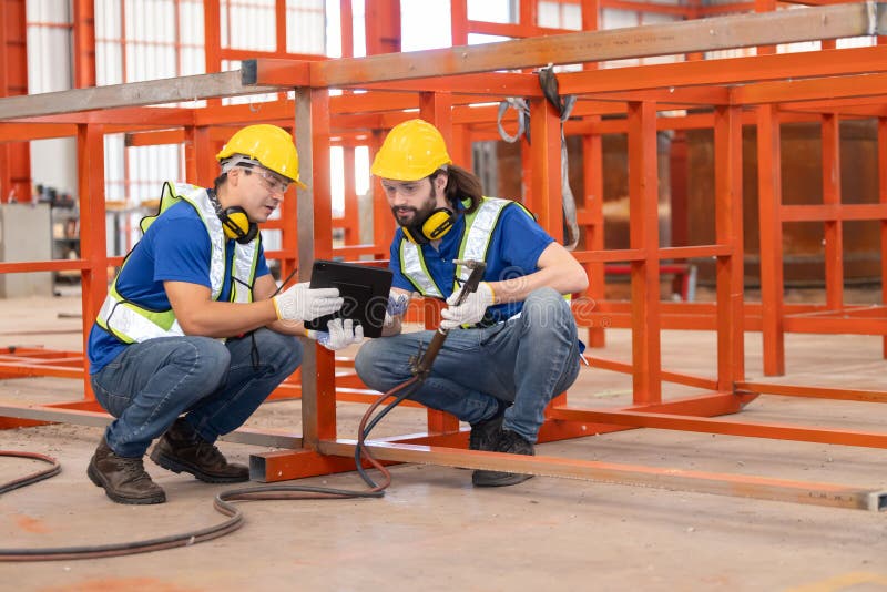 Caucasian Iron Welding Workers with Tablet in Front of the Red Steel ...