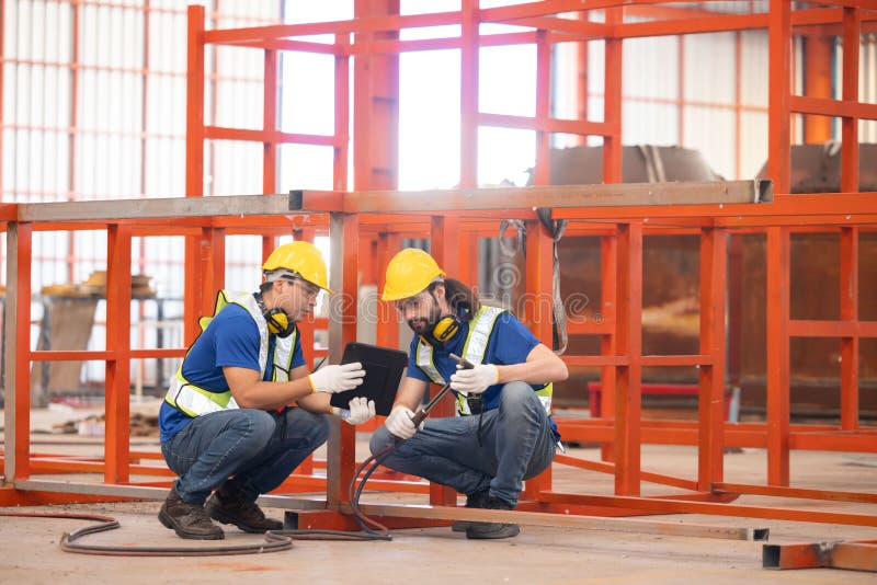 Caucasian Iron Welding Workers with Tablet in Front of the Red Steel ...