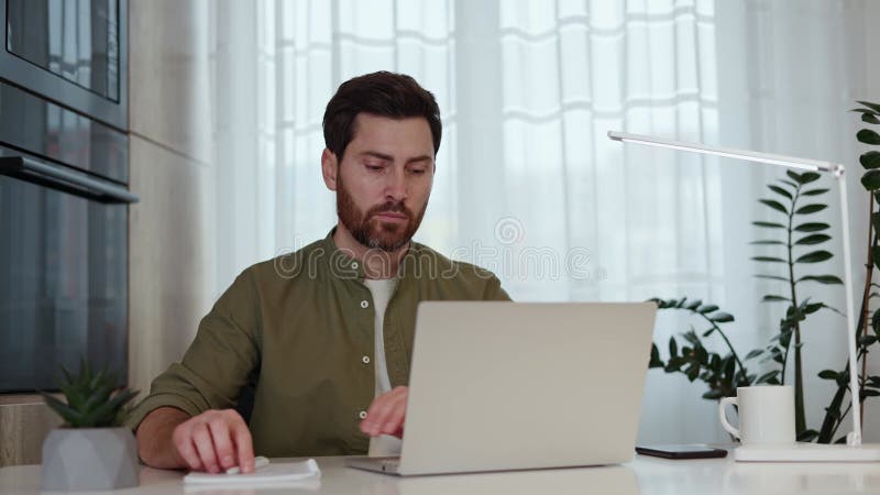 Caucasian Male Freelancer Using Notebook and Typing on Laptop in Home ...